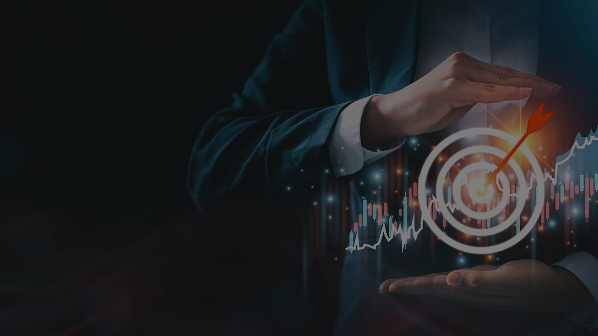 A business professional in a suit holds a digital graphic of a target with an arrow hitting the bullseye, overlaid with financial graph lines, symbolizing achieving business goals and financial success.